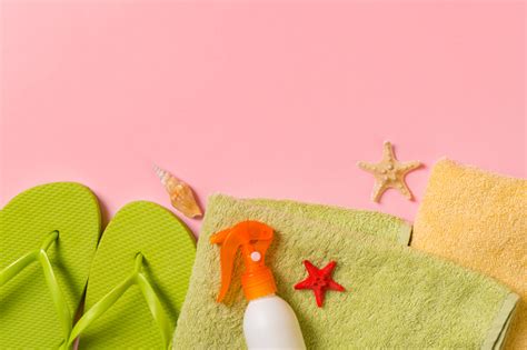 해변 플랫 레이 액세서리의 상단보기 조개 불가사리 수건 및 플립 플롭과 복사 공간이있는 컬러 배경의 선스크린 병 개념에 대한