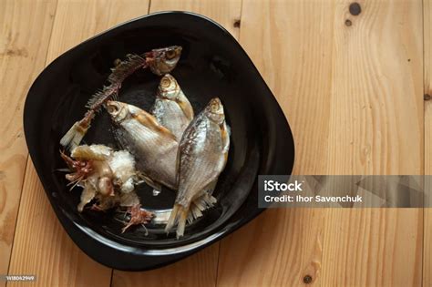 말린 생선 뼈 및 척추를 접시에 머리로 청소했습니다 물고기 해골 검은 접시에 소금에 절인 생선을 말렸다 맥주를위한 말린 생선