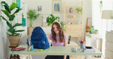 A Sad Girl Sits Sadly At Her Desk After Returning From School Stock