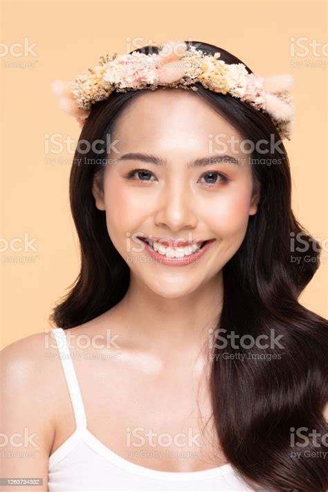 뷰티 아시아 젊은 여자 큰 꽃다발 꽃 머리 미소 와 깨끗 한 신선한 피부 행복과 쾌활 한 긍정적인 감정베이지 배경에 긍정적인