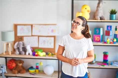 Young Beautiful Teacher Wearing Glasses Standing At Kindergarten Stock