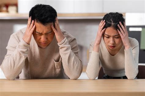 Premium Photo Upset Asian Spouses Sitting At Kitchen Desk Touching Heads
