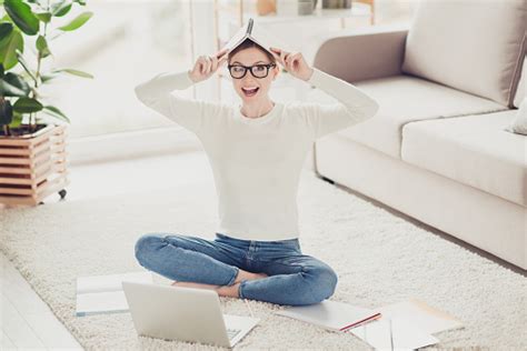 어리석은 매력적인 재미 있고 스마트 소녀 지붕 처럼 머리에 들고 노트북 교차 다리 집에서 카펫에 앉아 오픈 입으로 카메라를 보고 노트북 주변 Copybooks 데 가정