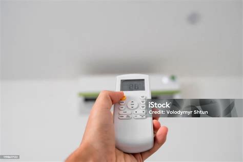 리모컨을 사용 하 여 사람의 손 손으로 Rc를 잡고 흰색 벽에 장착 된 에어컨의 온도를 조정합니다 인두어 쾌적 한 온도 건강