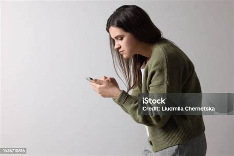 회색 배경에 스마트폰을 사용하는 나쁜 자세를 가진 젊은 여성 텍스트를 위한 공간 스마트폰에 대한 스톡 사진 및 기타 이미지