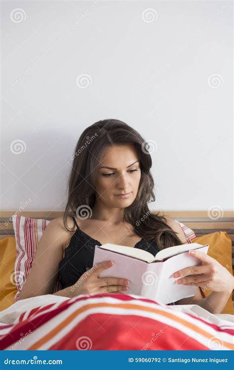 Beautiful Woman Reading Book While Lying In Bed At Home Stock
