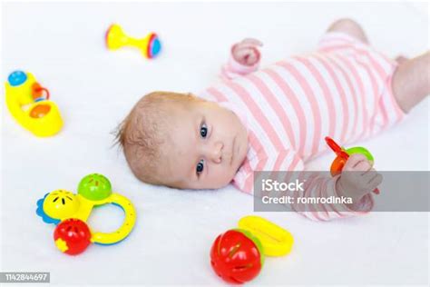 귀여운 사랑 스러운 신생아 흰색 바탕에 다채로운 흔들어 장난감을 많이 재생 새로운 태어난 아이 카메라에 놀란 어린 소녀 가족