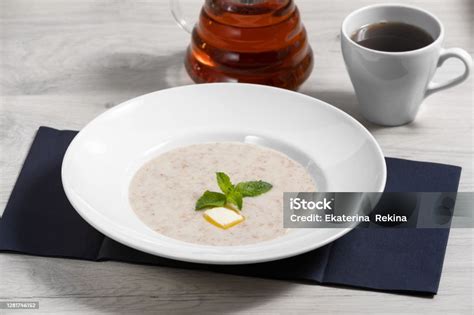 버터와 민트 잎이 달린 흰색 접시에 우유 죽을 차 한 잔과 함께 나무 배경에 놓습니다 건강한 아침 식사 적절한 아침 0명에 대한