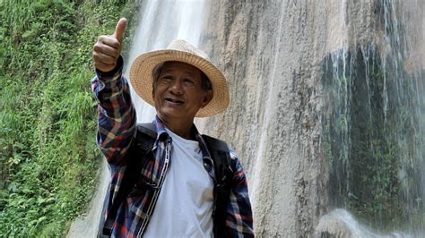 수석 아시아 행복 하 고 웃는 야외 가입 엄지를 보여주는 남자 폭포 배경 여행자입니다 관광 휴가 및 라이프 스타일 개념 노인에