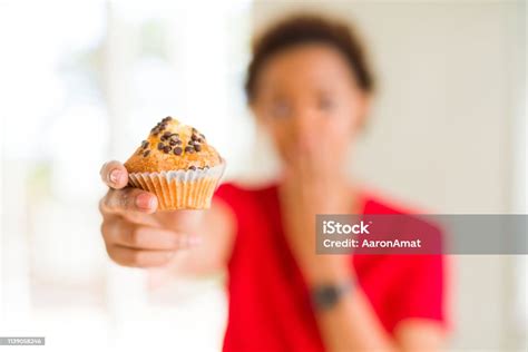 젊은 아프리카계 미국인 여자 먹는 초콜릿 칩 머핀 커버 실수에 대 한 수치심으로 충격 두려움의 표현 침묵에 무서 워 비밀 개념 가리기에 대한 스톡 사진 및 기타 이미지