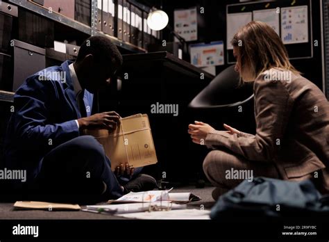 Private Detectives Working Overtime In Arhive Room Analyzing Crime Scene Evidence Discussing