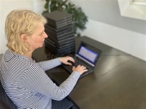 A Casually Dressed Caucasian Middle Aged Woman Is Installing A Laptop