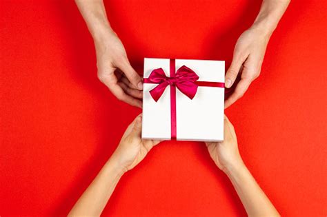 축하 배경 빨간 배경에 리본이 달린 선물 상자를 주고받는 두 사람의 손의 상단보기 맨 위 보기 받기에 대한 스톡 사진 및 기타 이미지 Istock