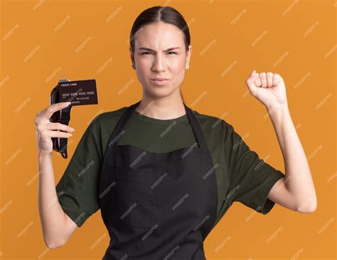 Free Photo Annoyed Young Brunette Barber Girl In Uniform Keeps Fist