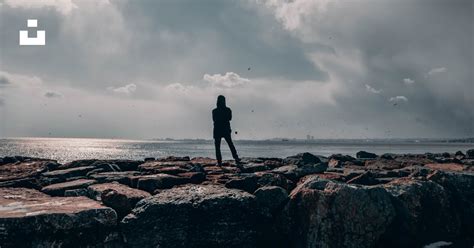 바다 근처의 바위 위에 서있는 사람 사진 Unsplash의 무료 회색 이미지