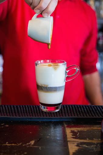 커피 피콜로 라떼 컵에 라떼 아트를 준비하기 위해 남성 바리스타 손을 잡고 뜨거운 우유를 붓는 클로즈업 갈색에 대한 스톡 사진