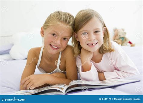 Duas Raparigas Em Seus Pijamas Lendo Um Livro Foto De Stock Imagem