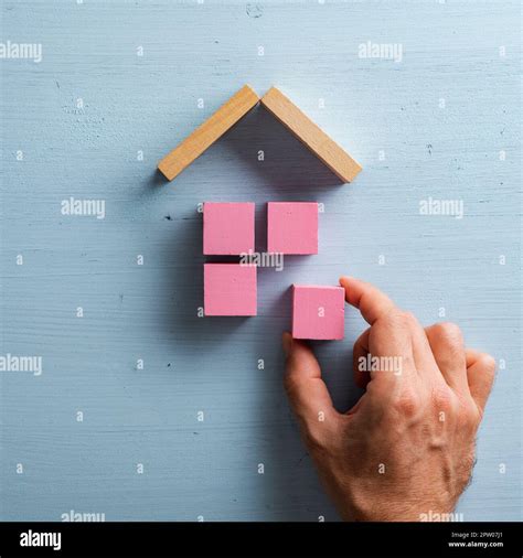 Male Hand Making A House Or Home Of Pink Wooden Blocks With A Roof