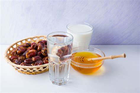 말린 날짜 우유와 흰색 바탕에 꿀 라마단의 거룩한 달 개념입니다 의로 운 이슬람 라이프 스타일 기아 나무 바구니와 꿀에 날짜