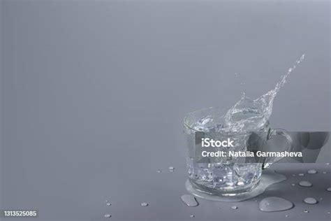 灰色の背景に透明なガラスコップの氷と透き通った水スプラッシュとスプラッシュ こぼすのストックフォトや画像を多数ご用意 こぼす しずく