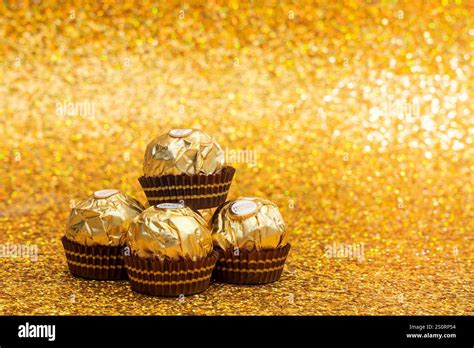 A Stack Of Ferrero Rocher Chocolates In Gold Wrapper On A Gold