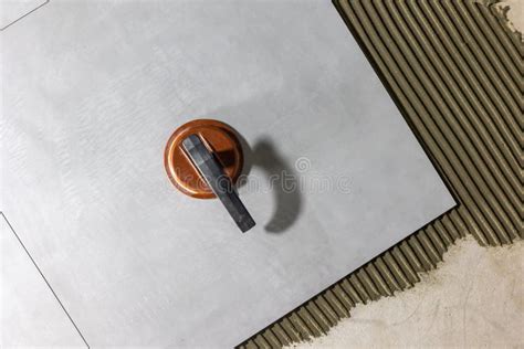 Tiler Worker Placing Or Tiling Gray Ceramic Tile In The Position Over