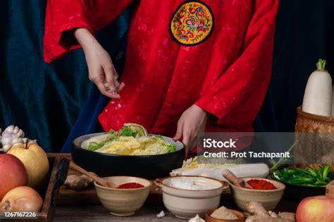 한국 전통 의상을 입은 아시아 여성들은 손으로 소금을 뿌리고 김치식에는 마늘 고추가루 신선한 채소 등의 재료가 들어 있습니다