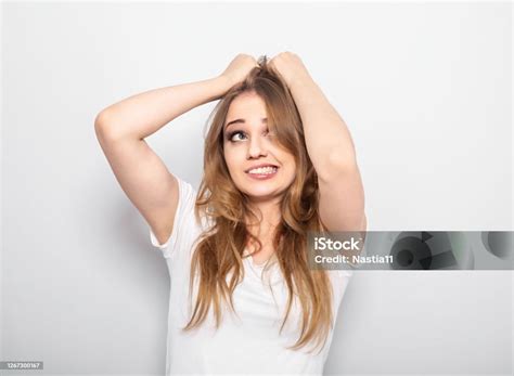 금발을 생각하면 얼굴을 찡그리는 여자가 위를 쳐다보며 밝은 파란색 배경에 손을 잡고 생각 빈 복사 공간이 있는 클로즈업