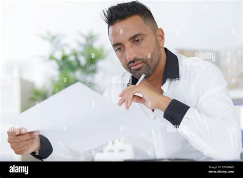Male Architect Verifying Data Information From Map On Blueprint Stock