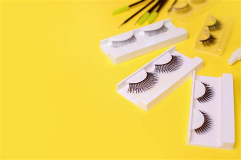 트렌디 한 밝은 노란색 배경에 눈 속눈썹 확장을위한 다른 도구 가짜 속눈썹 브러쉬 점토 뷰티 컨셉 메이크업 화장품 텍스트 와