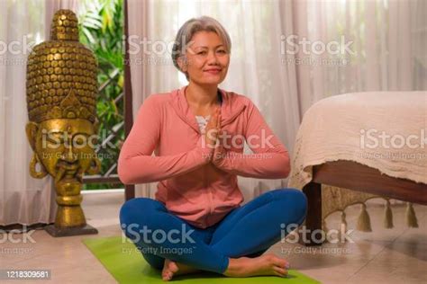 홈 라이프 스타일 아시아 데코 침실에서 요가와 명상 운동을하고 그녀의 50 년대에 회색 머리와 아름답고 행복한 성숙한 여성은 웰빙과 건강한 노화의 평화롭고 균형을 느끼고