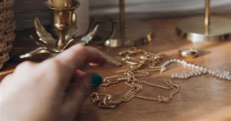 현대적인 금과 진주 액세서리와 빈티지 촛대가 있는 테이블에 흐릿한 여성 손 세련 된 황금 목걸이와 화창한 빛에 나무 배경에 반지 사진 Unsplash의 써니 이미지