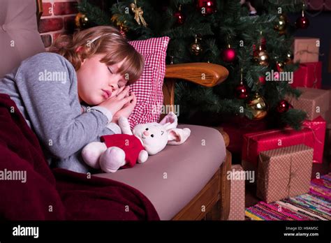 Girl Sleeping Under A Blanket On The Sofa Near The Christmas Tree With