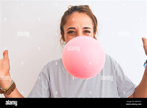 Young Redhead Woman Chewing Gum And Blowing Hair Bubble Over White