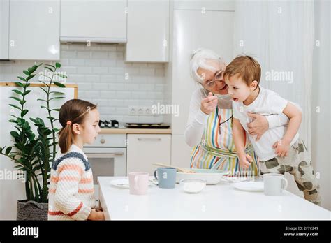 Granny énergique Tenant Son Petit Fils Debout Sur Un Tabouret L