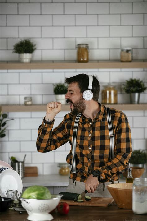 부엌에서 노래하는 젊은 매력적인 남자 부엌에서 재미있게 놀고 있는 잘생긴 남자 사진 Unsplash의 복사 공간 이미지