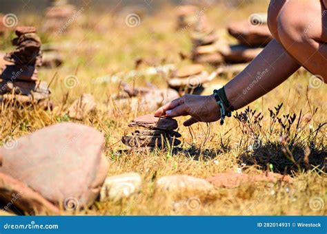Woman Putting Little Piles Of Stones In The Pregonda Cove Of Menorca