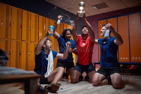 Group Of Men In Dressing Room Celebrating Victory Holding Gold Medal