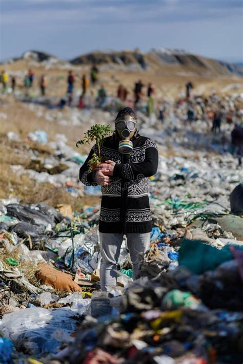 Man With Gas Mask And Plant On Landfill Standing On Landfill Large