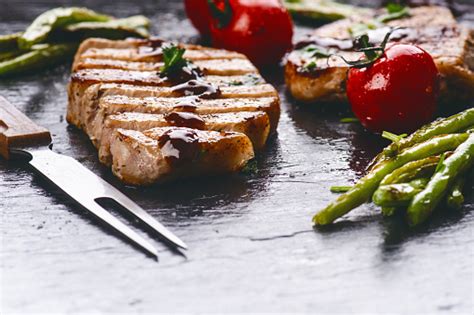 구운된 돼지고기 볶음 야채 토마토 콩 블랙 슬레이트에 소스와 스테이크 거품과 신선한 고기입니다 어두운 배경입니다 구이 및 바베 큐 개념 가금류에 대한 스톡 사진 및 기타