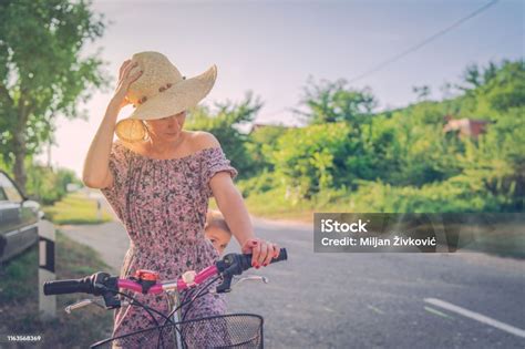 야외 오픈 로드 아스팔트에서 드레스와 모자를 입고 여름 화창한 날에 자전거를 밀어 가는 핸들 바 그립을 들고있는 젊은 여성 거리에 대한 스톡 사진 및 기타 이미지 Istock