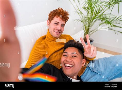 Beautiful Gay Couple Being Romantic Indoors At Home On The Sofa Gay