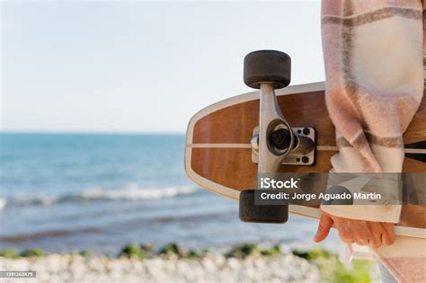 앞쪽에서 셔츠와 청바지를 입고 양손으로 롱 보드를 들고 바다로 향하는 여성의 절반 이미지 갈색에 대한 스톡 사진 및 기타 이미지 갈색 관광 관광객 Istock