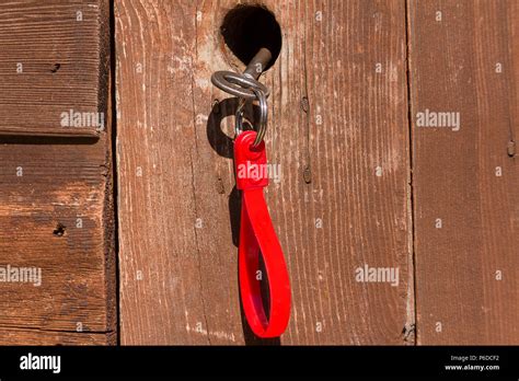 Shed Lock And Key With Bright Red Tag Against Weathered And Worn Timber
