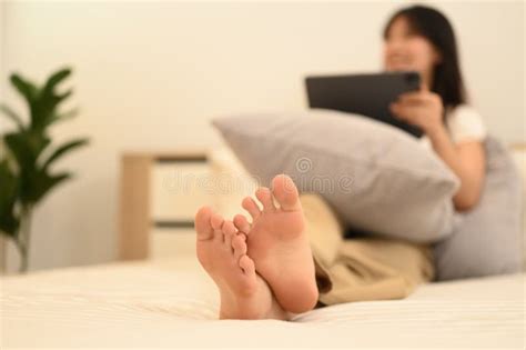 Select Focus On Female Feet Lying In Bed And Using Digital Tablet Stock