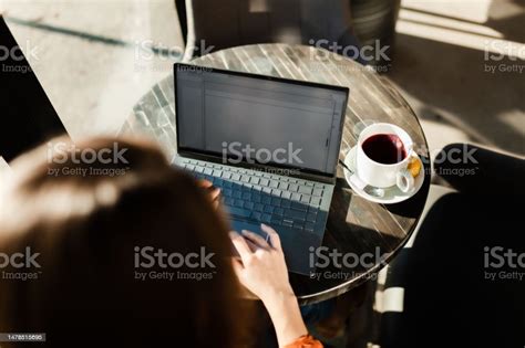 밝은 햇빛이 비치는 카페 바 또는 레스토랑에서 젊은 사업가 노트북으로 작업하고 창가 테이블에서 차를 마시는 프리랜서 소녀 추상