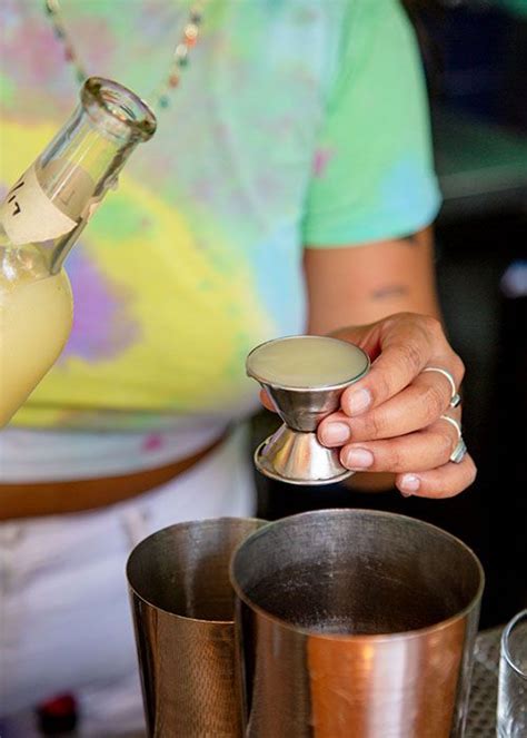 A Woman Is Pouring A Drink Into Two Cups