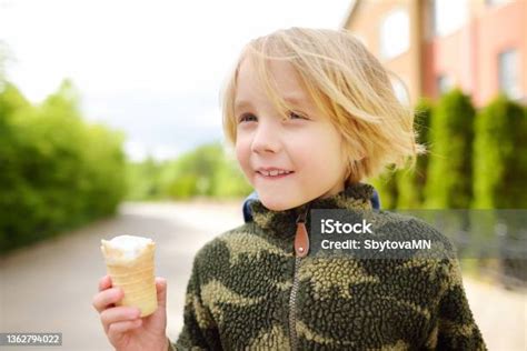 가족 산책 하는 동안 야외에서 맛있는 아이스크림을 먹는 어린 소년 어린이는 이동 중에서 간식을 먹습니다 젤라토는 아이들의 섬세함을 사랑받고 있습니다 거리에 대한 스톡 사진