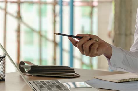 건설 현장 시공업체 엔지니어링 및 건설 개념에서 새로운 프로젝트 계획을 논의하는 동안 랩톱 컴퓨터의 펜과 책상 위에 있는 청사진을 가리키는 프로젝트 관리자 손 개발에 대한