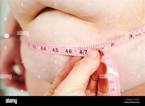 Nurse In Local Hospital Using A Tape Measure To Calculate BMI And